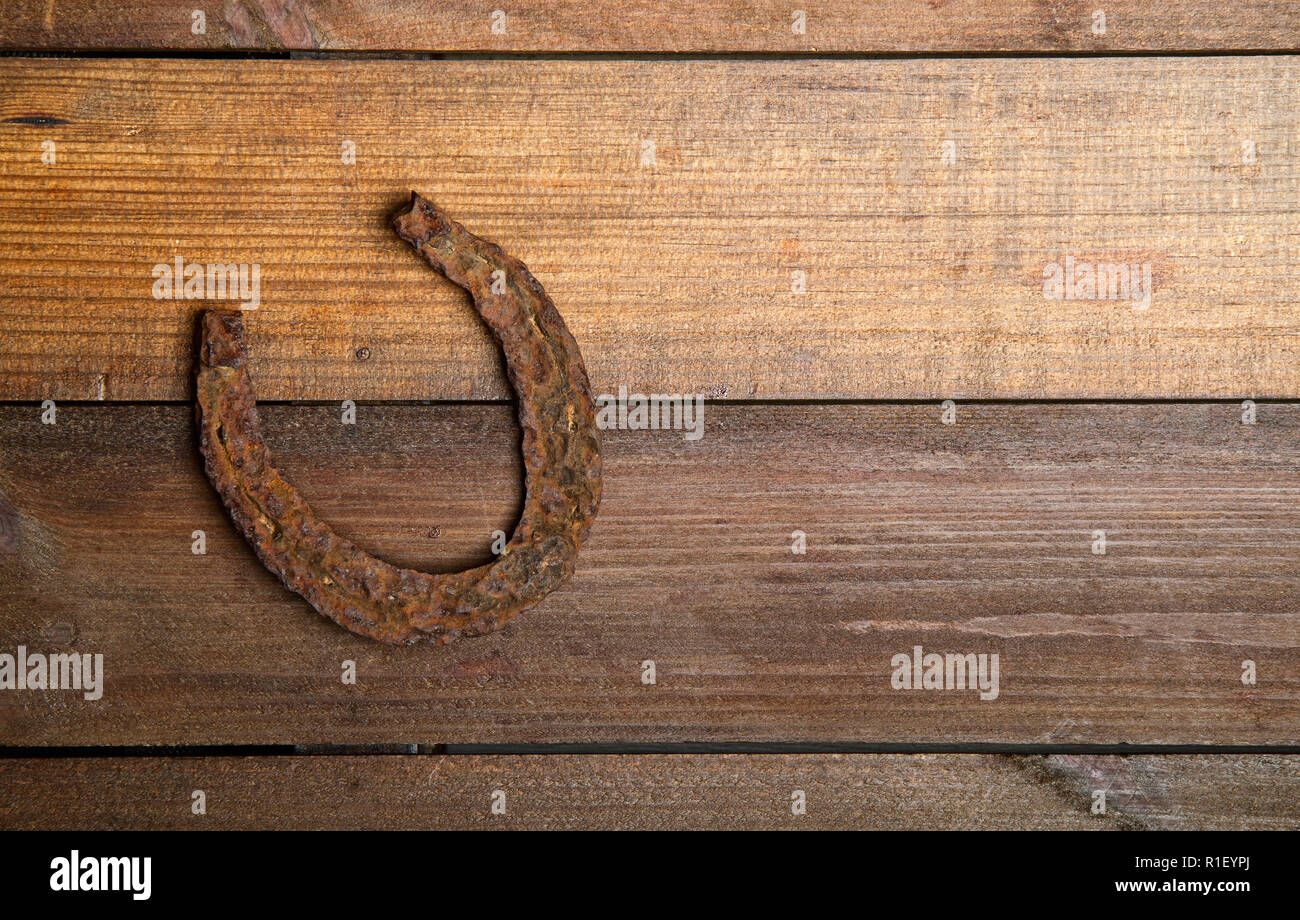 a very old and rusty horseshoe symbol of luck on a simple wooden ...