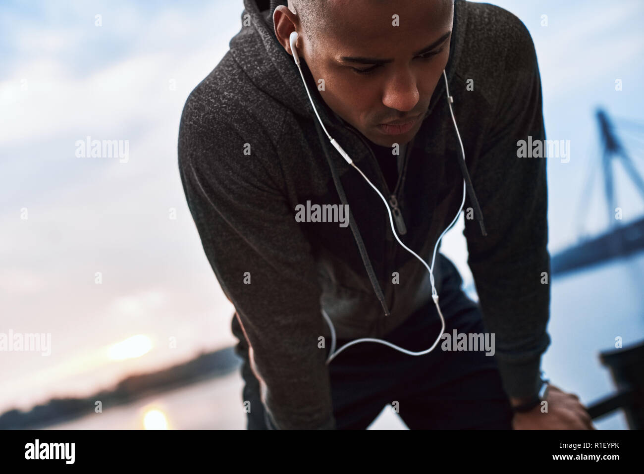 Tired because of running. Young jogger is stopped to catch his breath ...