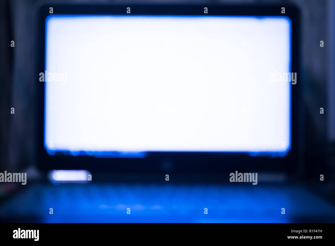 Abstract blur laptop computer on table and blue light shining from the ...