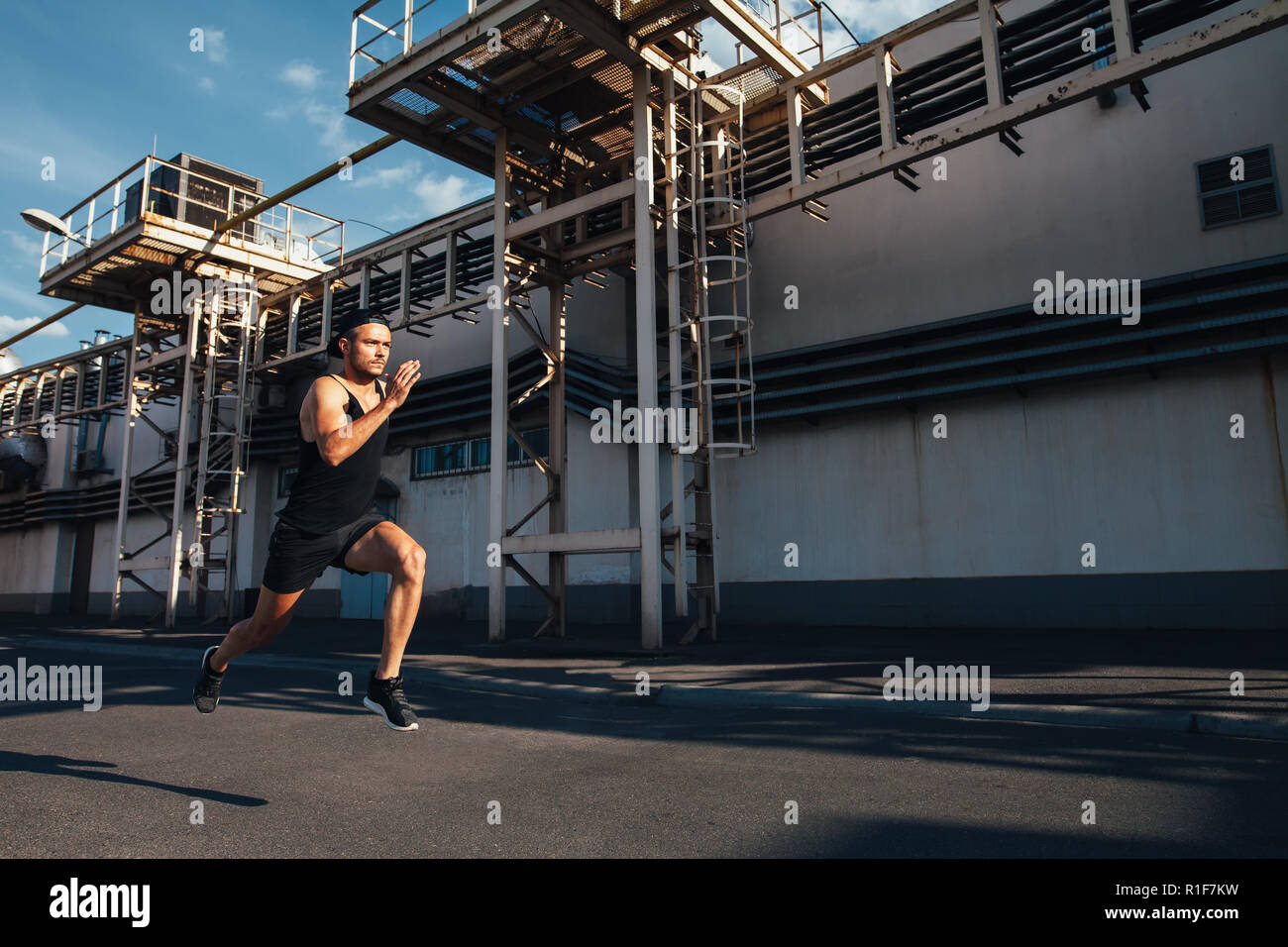 Runner man running fast in industrial city background. Sport, athletics ...