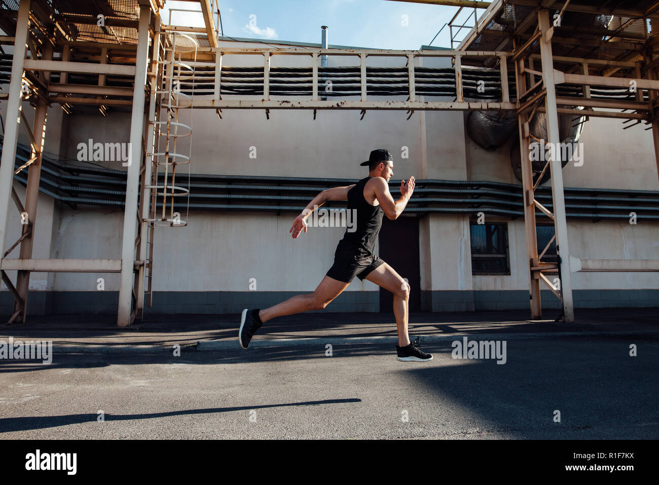 Sporty man running fast in industrial city background. Sport, athletics ...