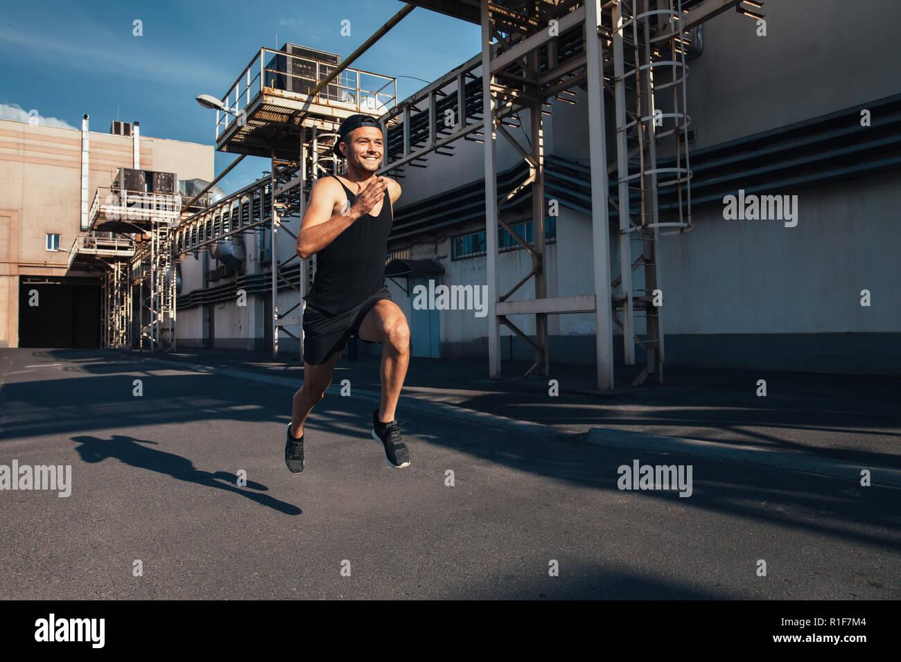 Smiling man running fast in industrial city background. Sport ...
