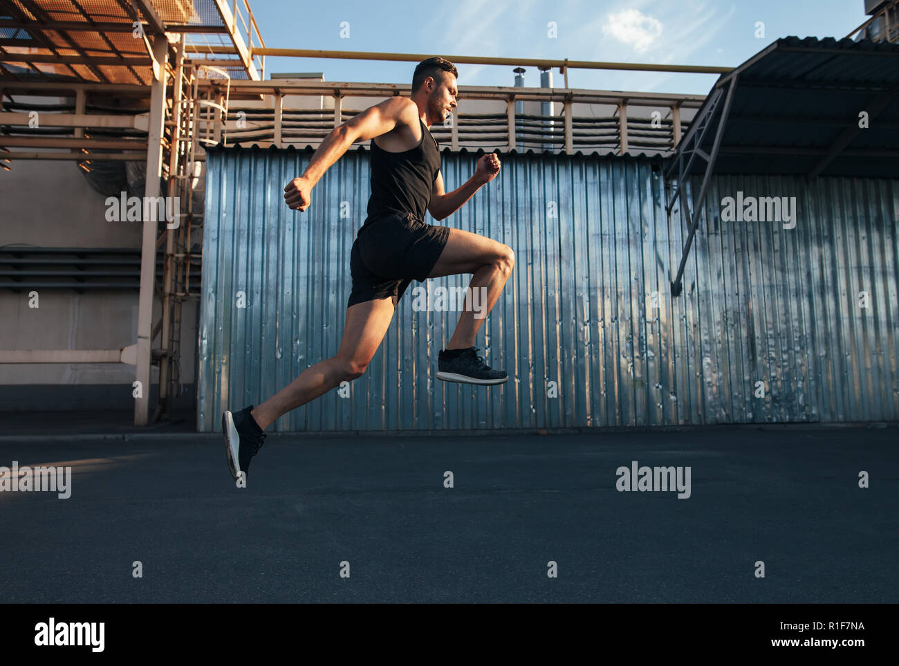 Handsome young man running in ndustrial building background. runner ...