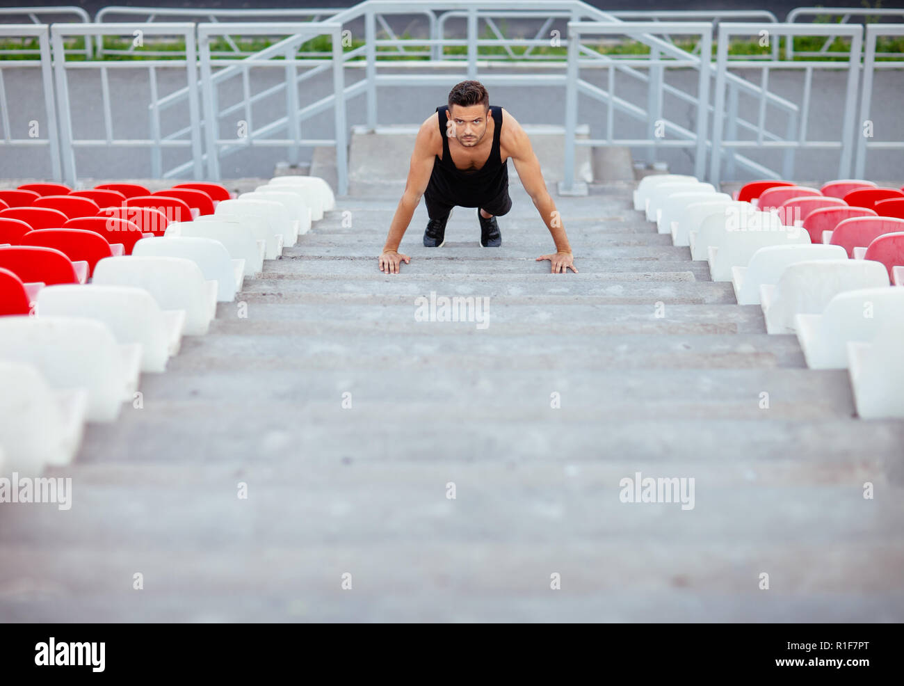 Serious man doing pushups on stadium stairs. Top view. Fitness, sport ...