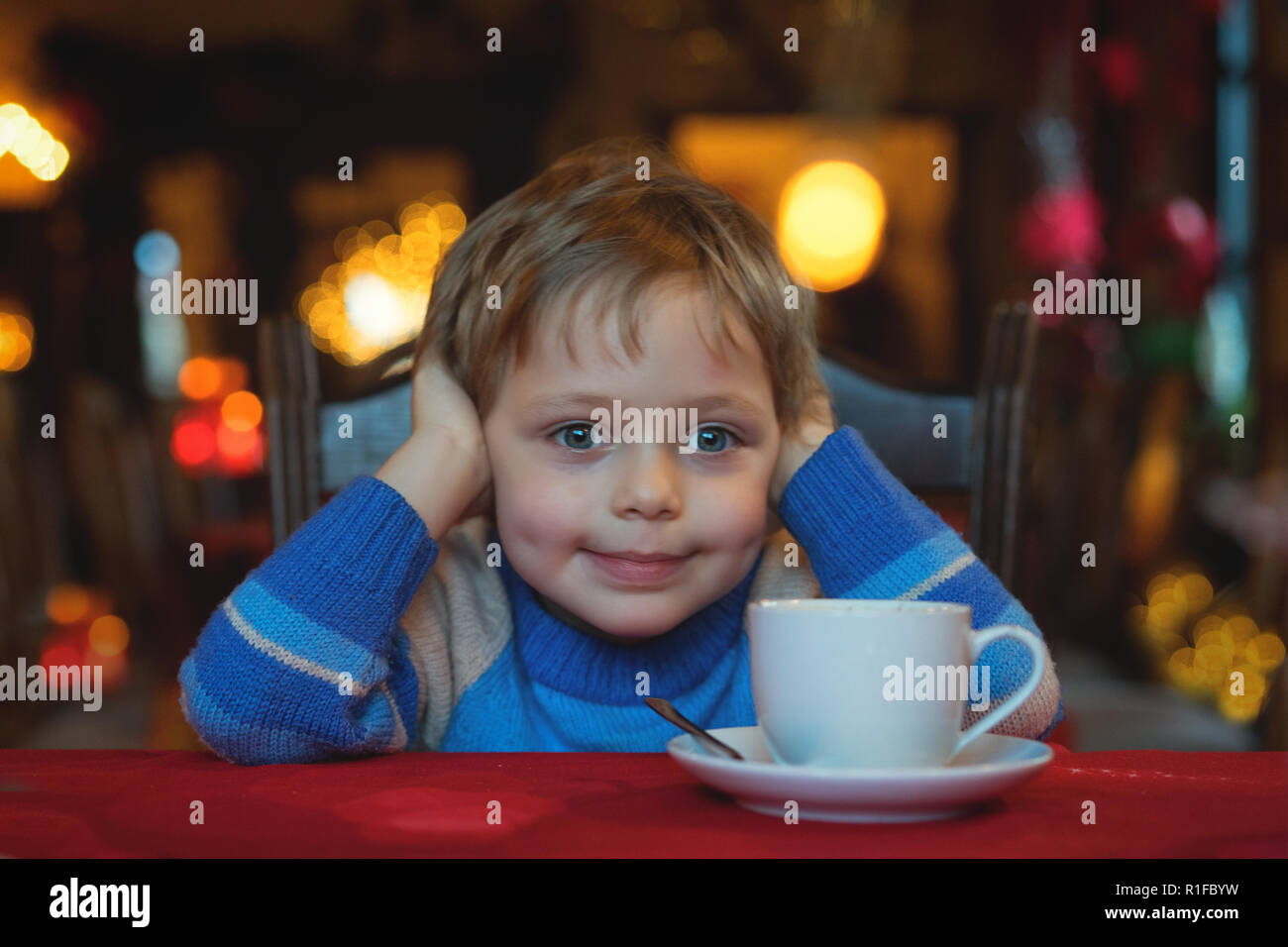 8 year boy drinking tea in cafe with christmas lights Stock Photo - Alamy
