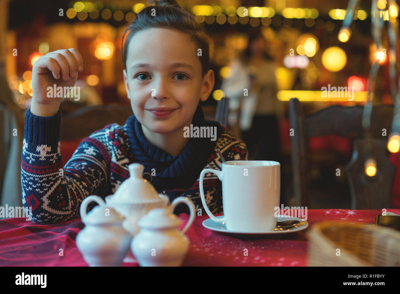 8 year boy drinking tea in cafe with christmas lights Stock Photo - Alamy