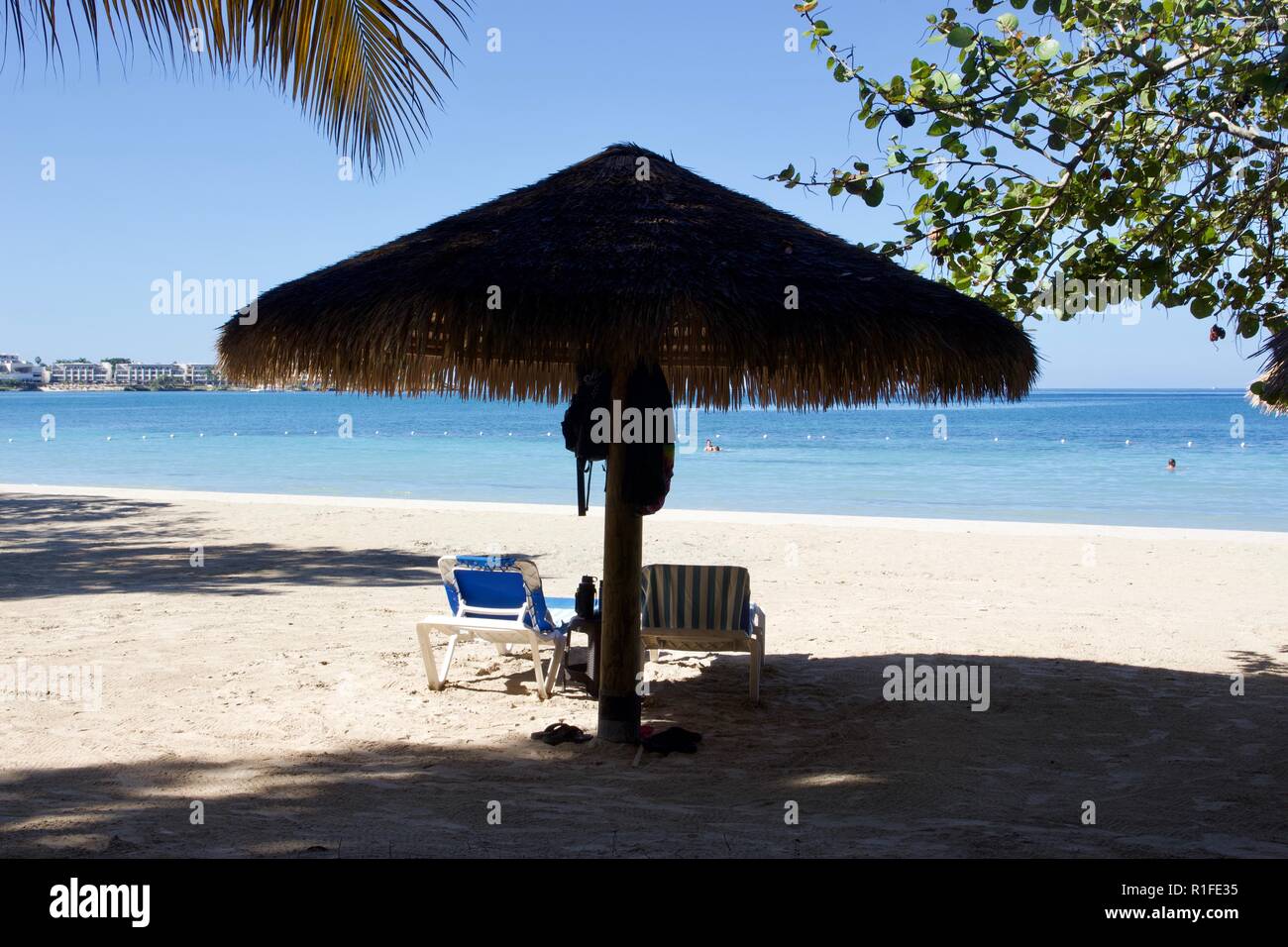 Beach shade provided by a thatched straw umbrella Stock Photo - Alamy
