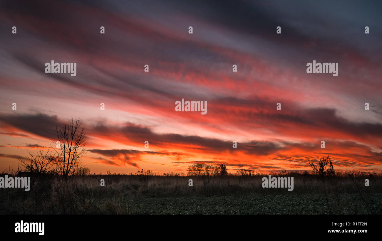 Clouds passing through a sunset over a flat field Stock Photo - Alamy