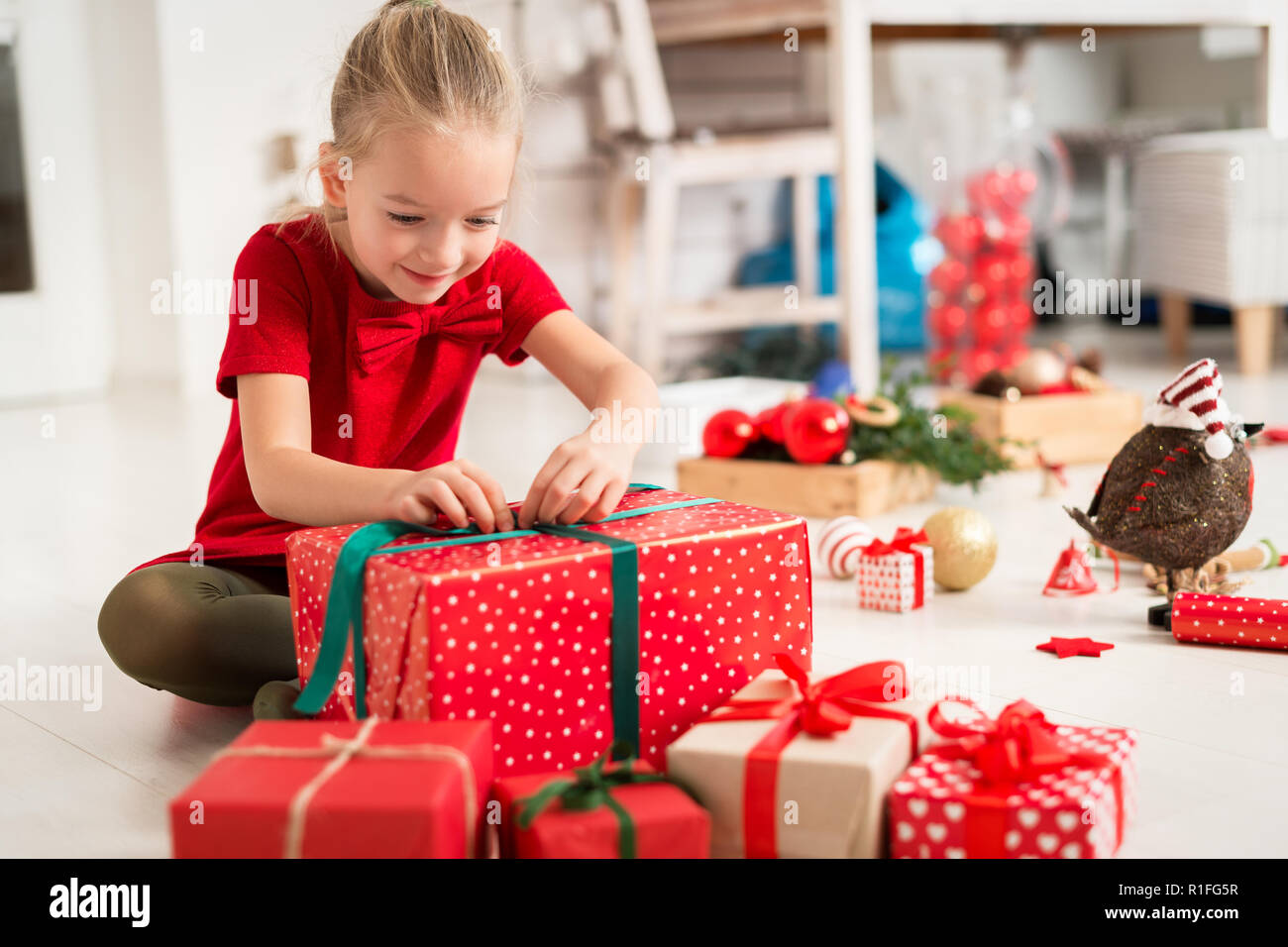 Cute super excited young girl opening large red christmas present while ...