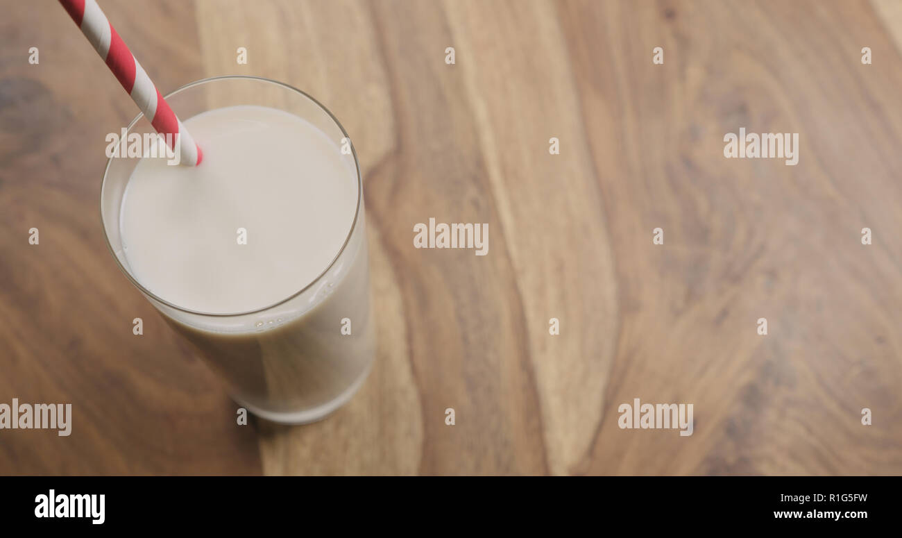 Oat milk in glass with red paper straw on wood background with copy ...