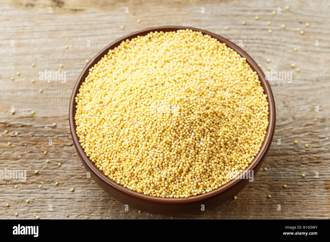 plate with raw cereal millet on a wooden background. preparation of a ...
