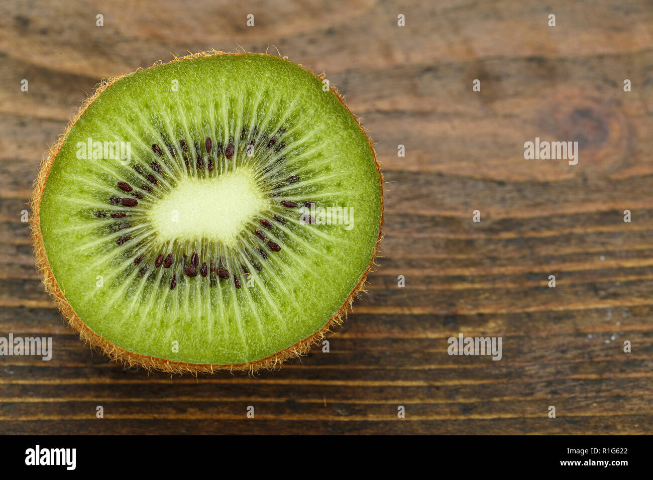half sliced kiwi on a wooden background. place for text. well visible ...