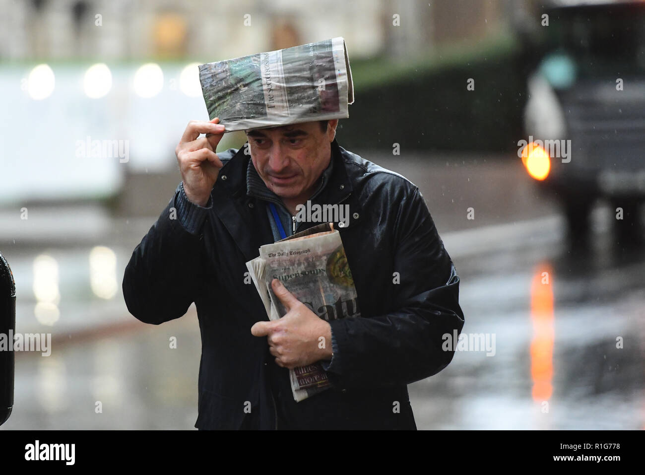 A man takes shelter from the rain beneath a newspaper in London Stock ...