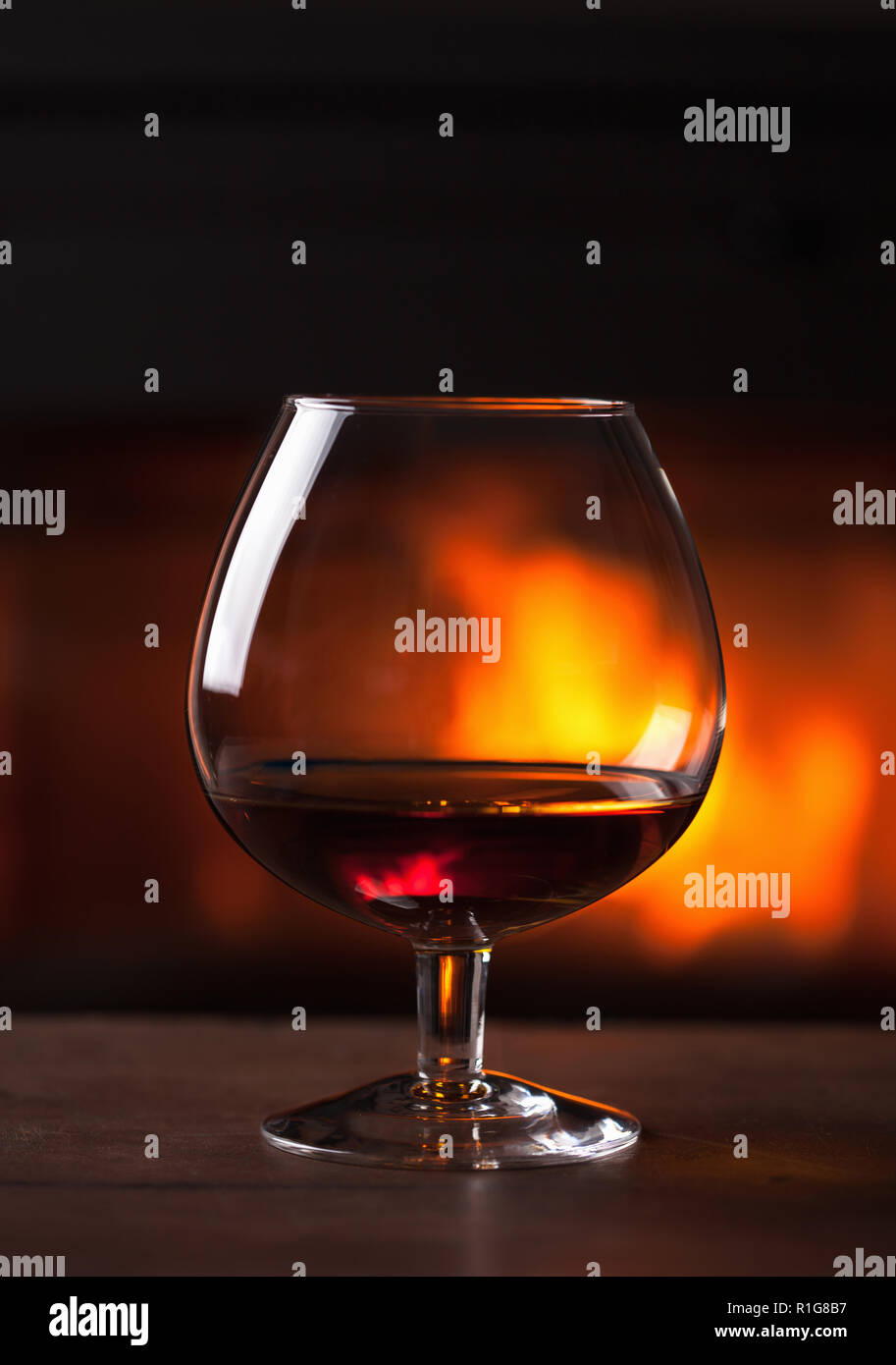 glass of cognac in front of fireplace Stock Photo - Alamy