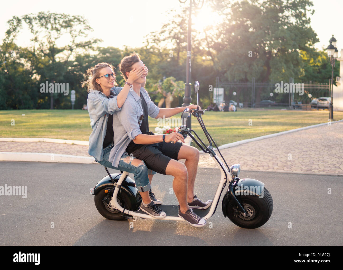 Lovely young happy couple driving electric bike Stock Photo - Alamy