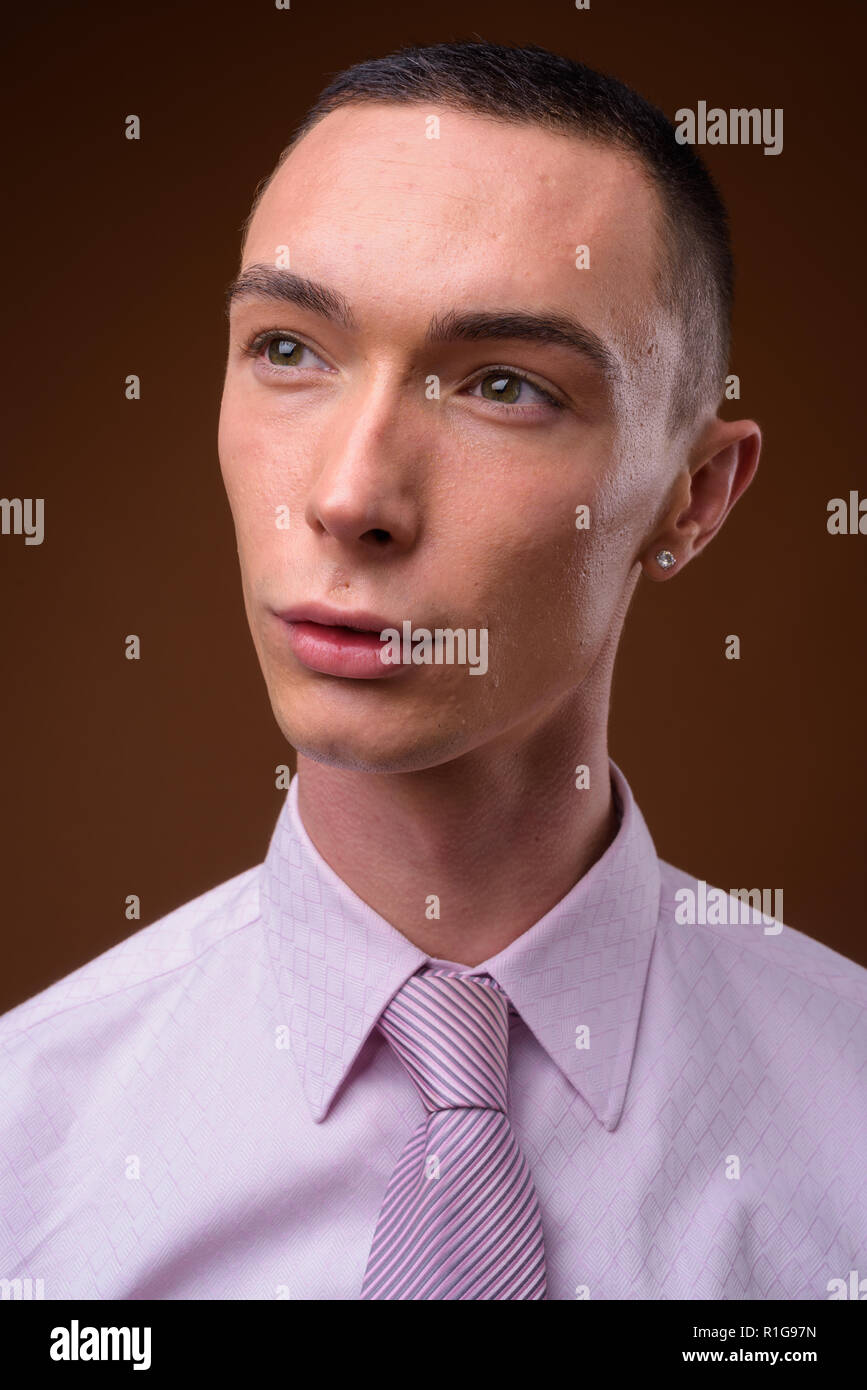 Young handsome androgynous businessman against brown background Stock ...
