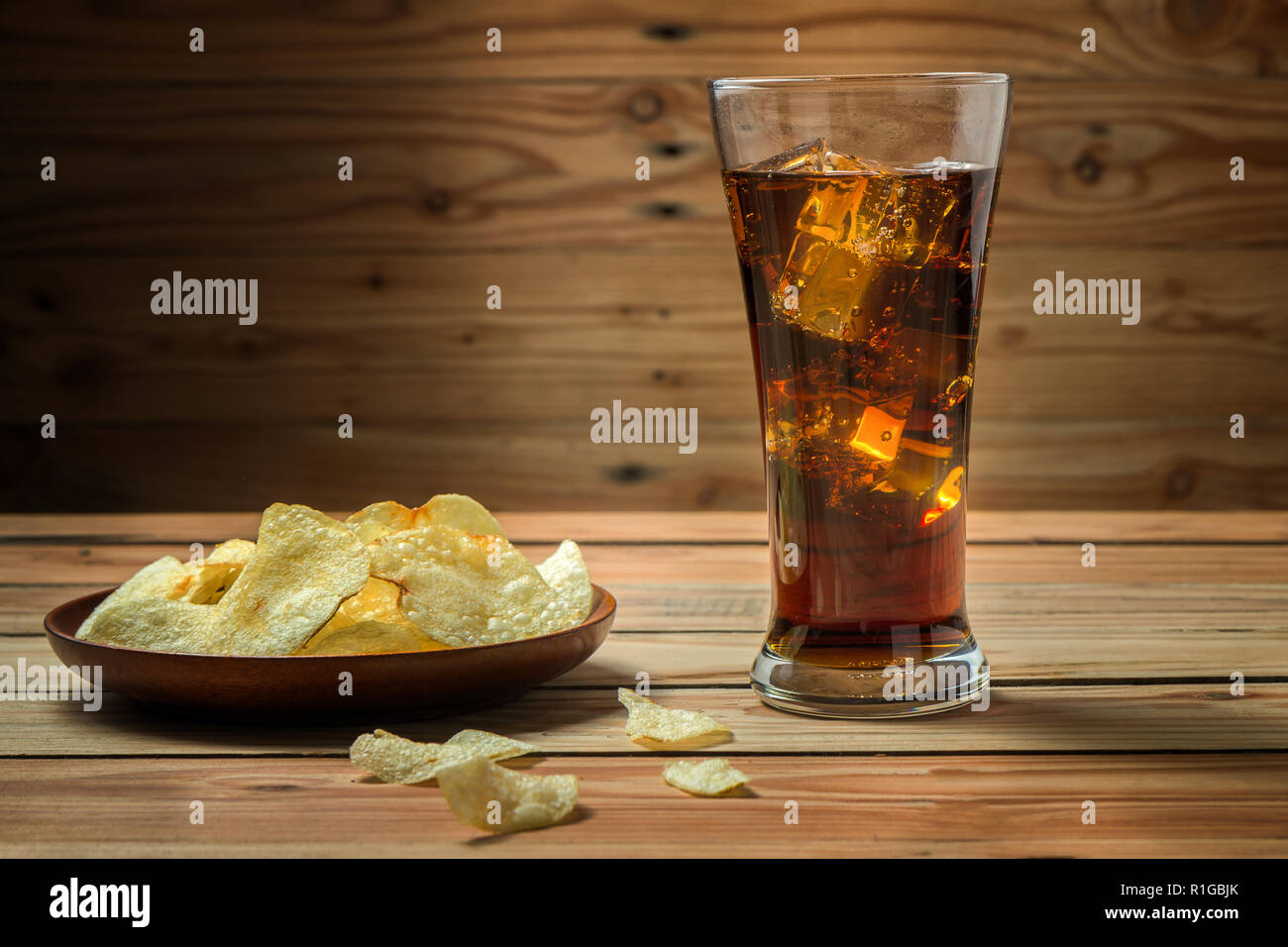 Potato chips with cola on a wooden background Stock Photo - Alamy