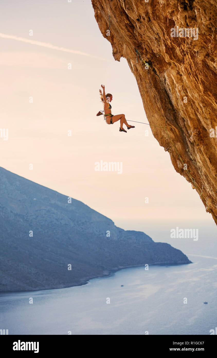 Female rock climber falling of a cliff while lead climbing at sunset ...