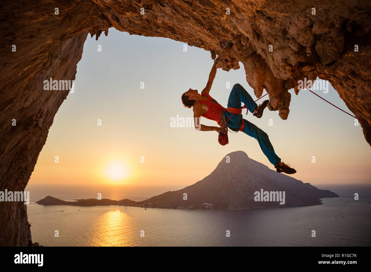 Male rock climber hanging with one hand on challenging route on cliff ...