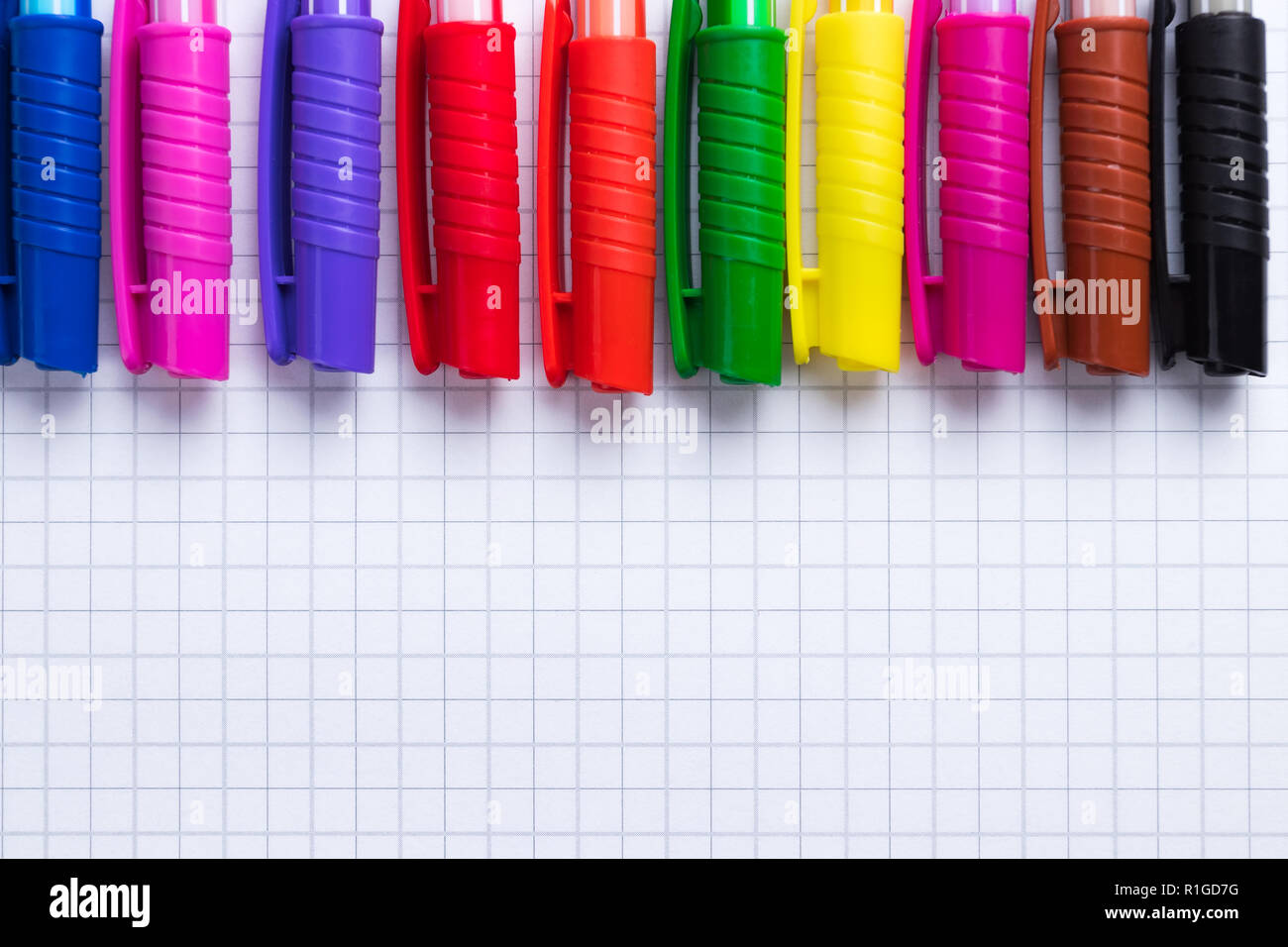 Colorful pens in a row on sheet of squared paper. Education abstract ...