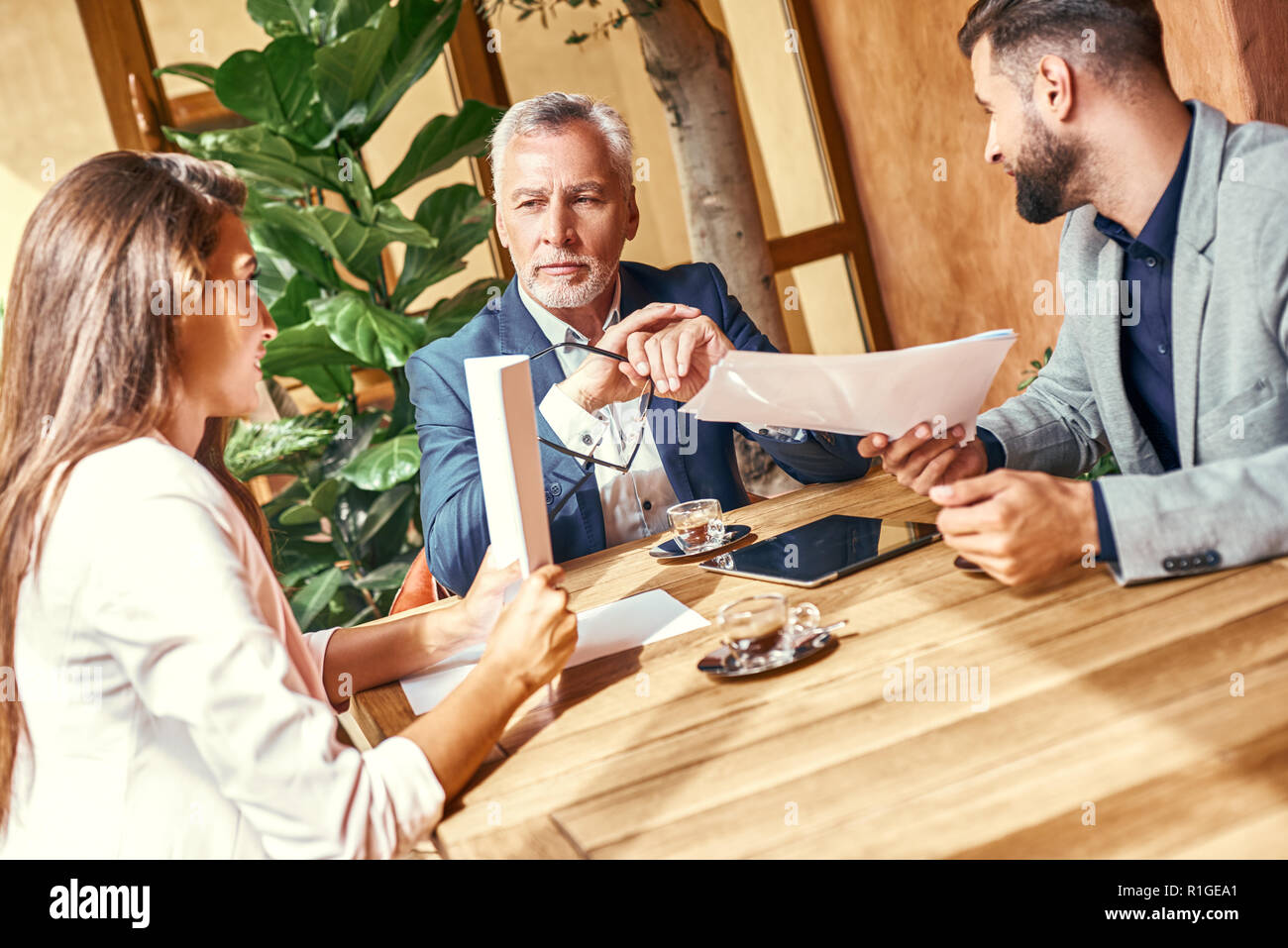 Business lunch. Three people in the restaurant sitting at table ...