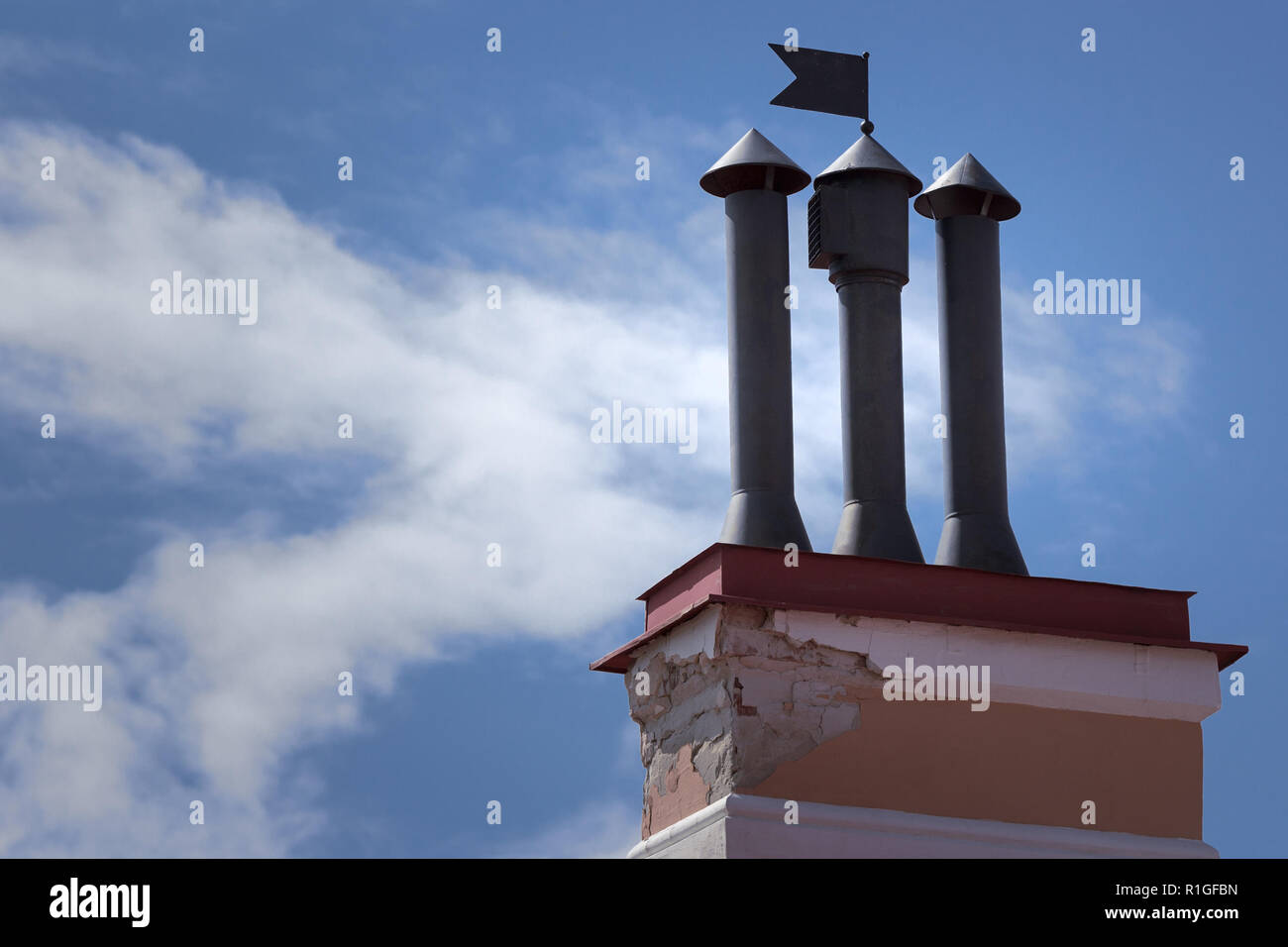 Roof chimney with wind vane, blue sky background Stock Photo - Alamy