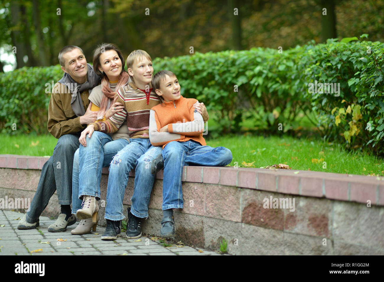 Portrait of family of four sitting in park Stock Photo - Alamy