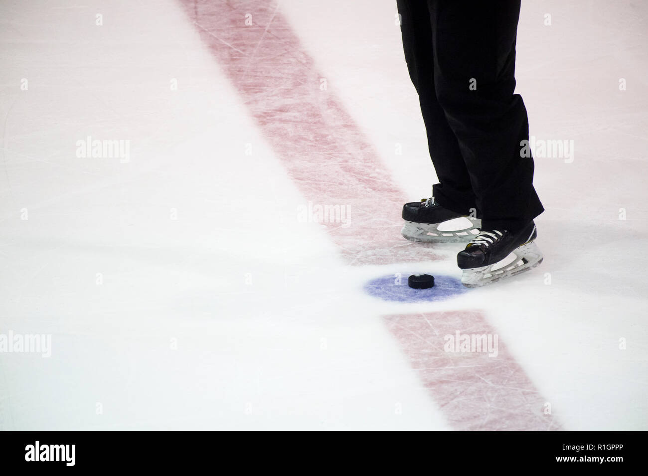 black hockey puck and referee legs on ice rink. Winter sport Stock ...