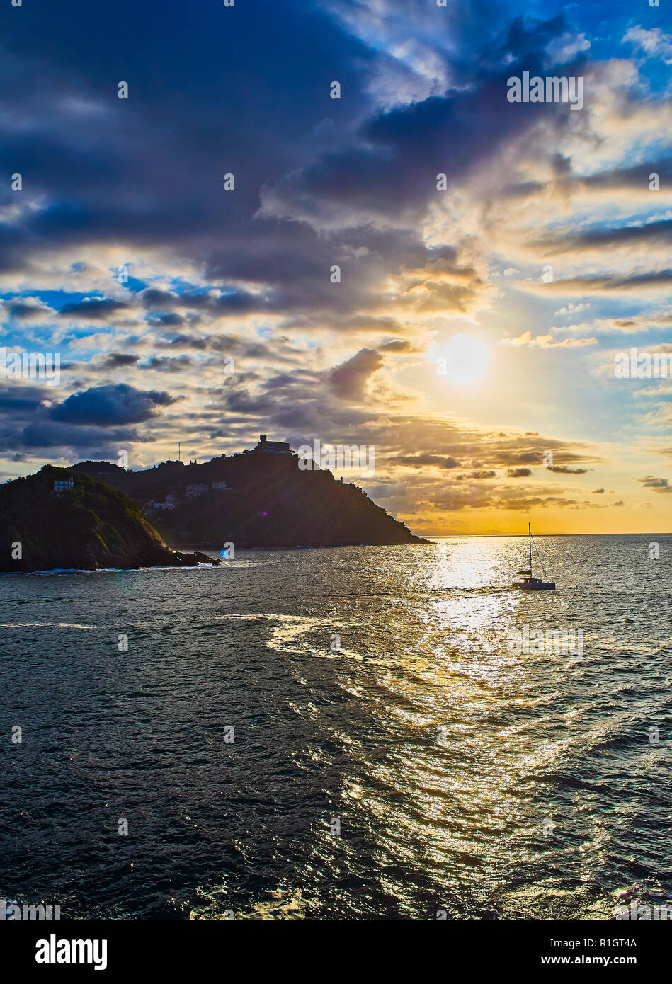 The sun sets behind the Santa Clara Island and The Monte Igueldo Mount ...