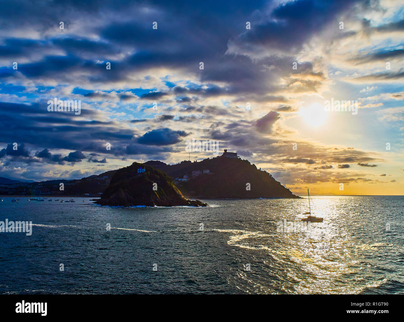 The sun sets behind the Santa Clara Island and The Monte Igueldo Mount ...