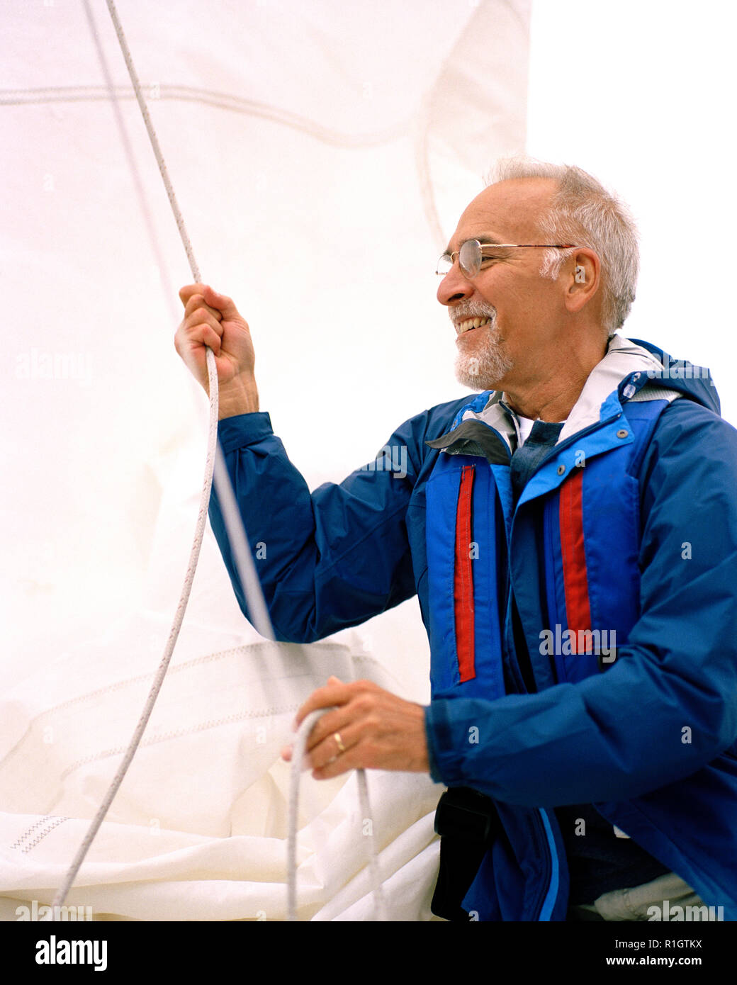 Man pulling sail rope on sailboat Stock Photo - Alamy