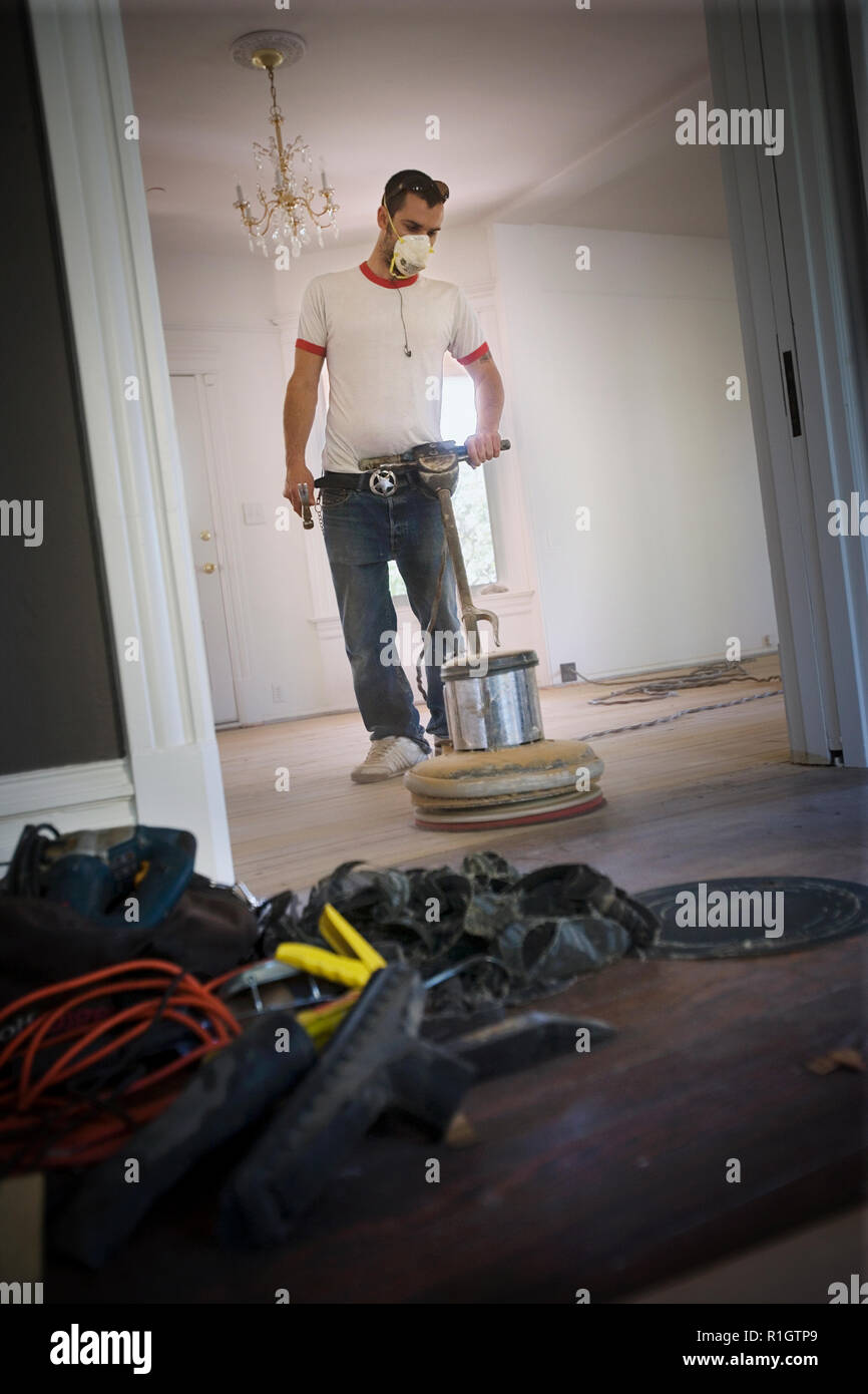 Male builder buffing floorboards inside a room Stock Photo - Alamy
