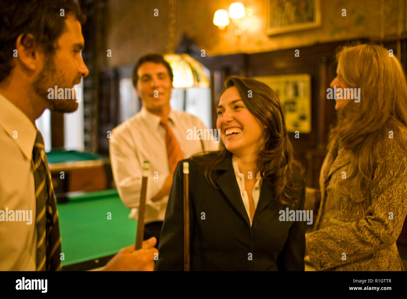 Smiling young adult business woman holding a pool cue while in a pool ...