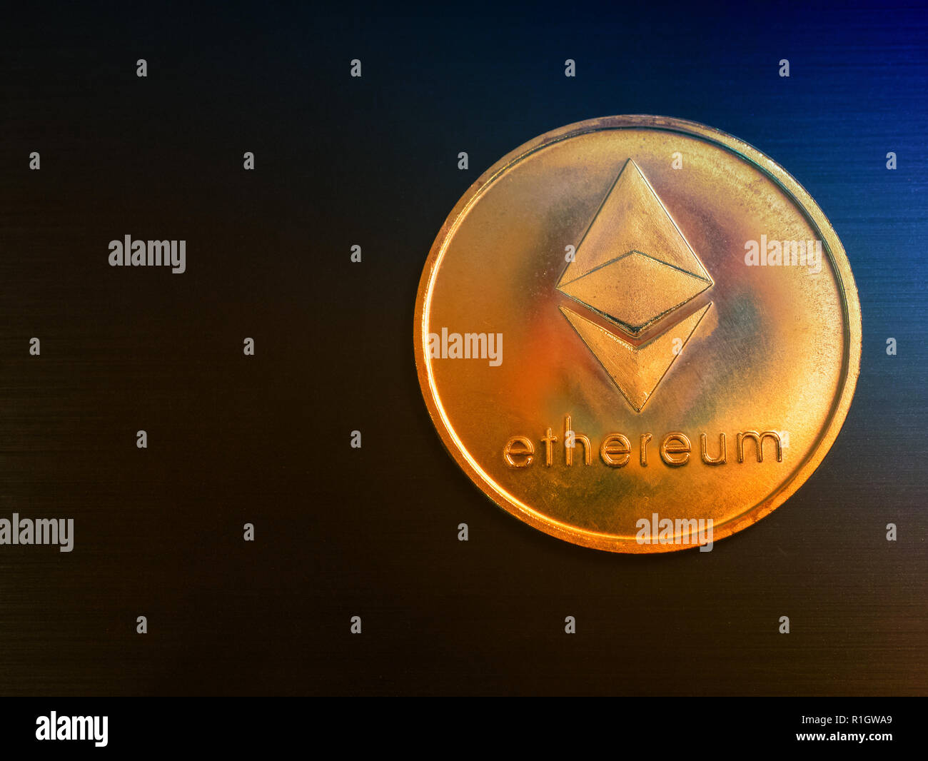 one ethereum gold coin on black metal surface as background. low key ...