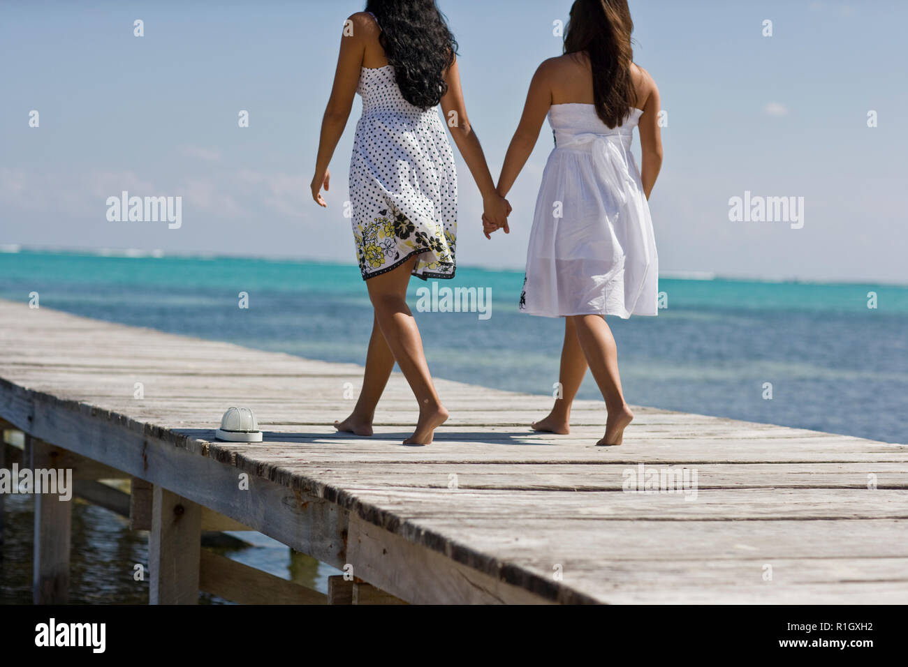 Two young adult girls walking along a jetty by the beach Stock Photo ...