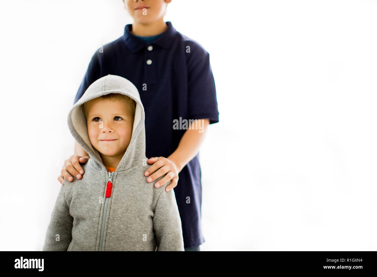 Portrait of a young boy standing in front of his older brother Stock ...