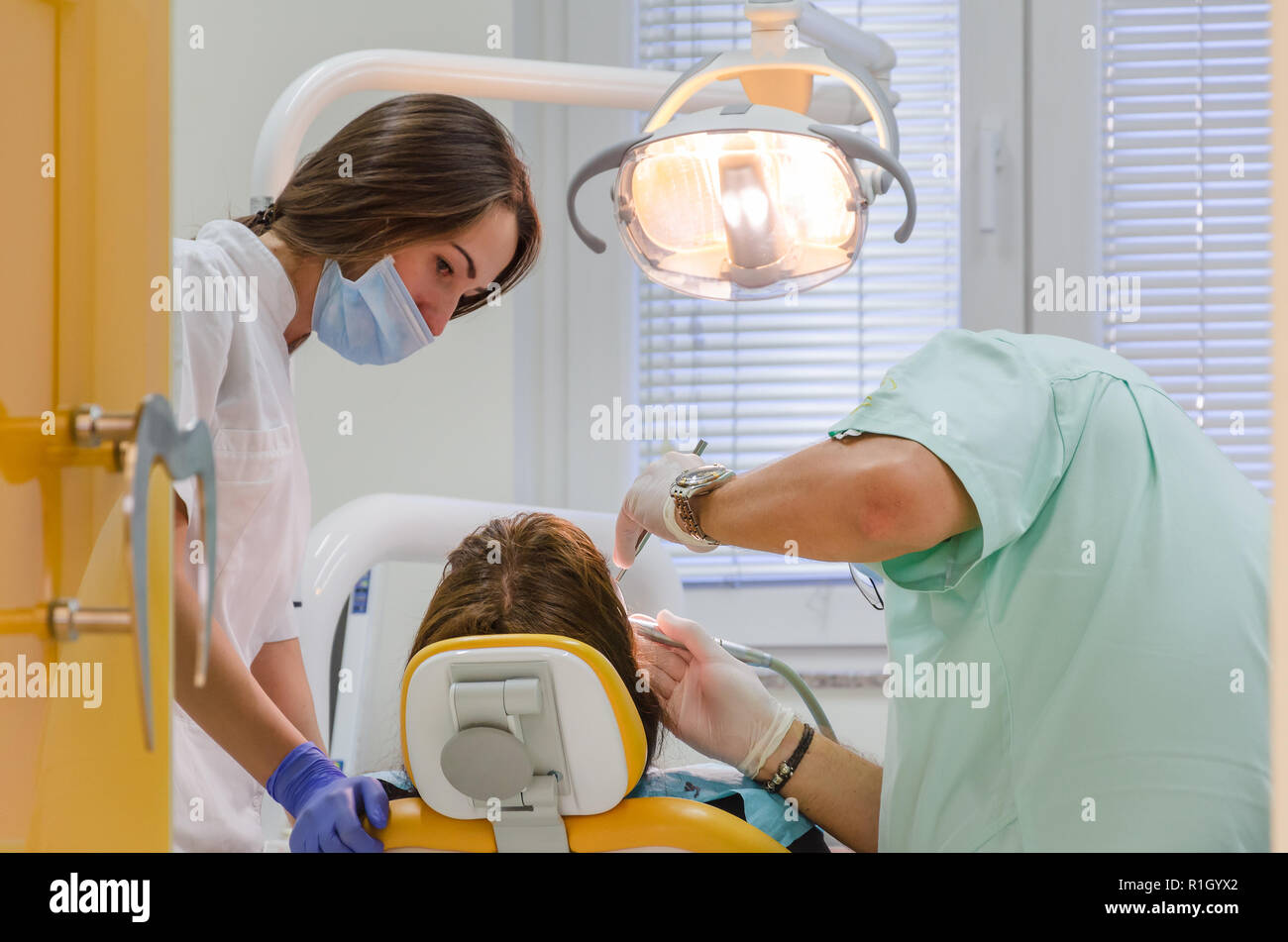 Doctor with nurse doing tooth operation to a patient in dentist office ...