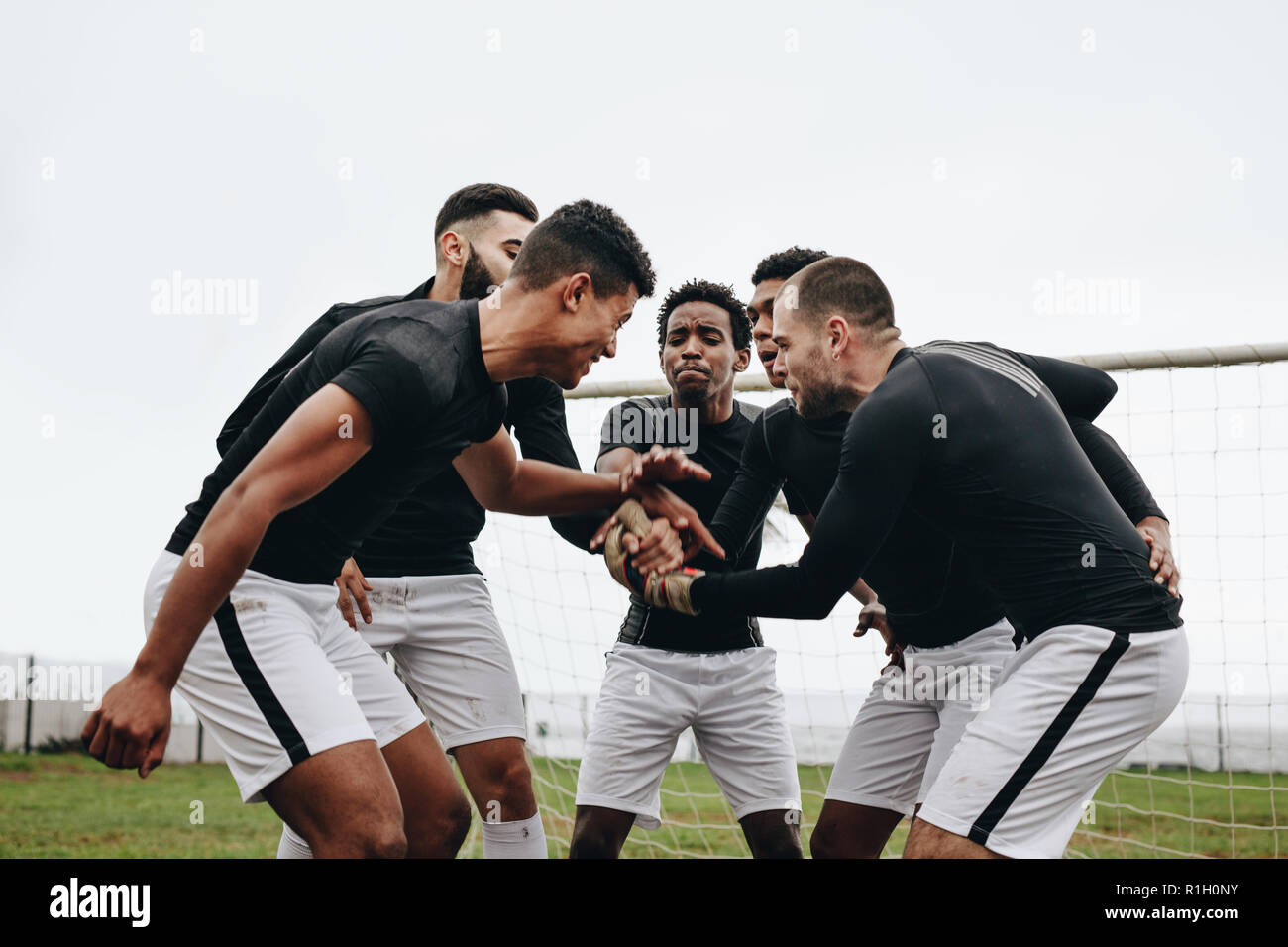 Soccer players holding their hands standing in a huddle and cheering ...