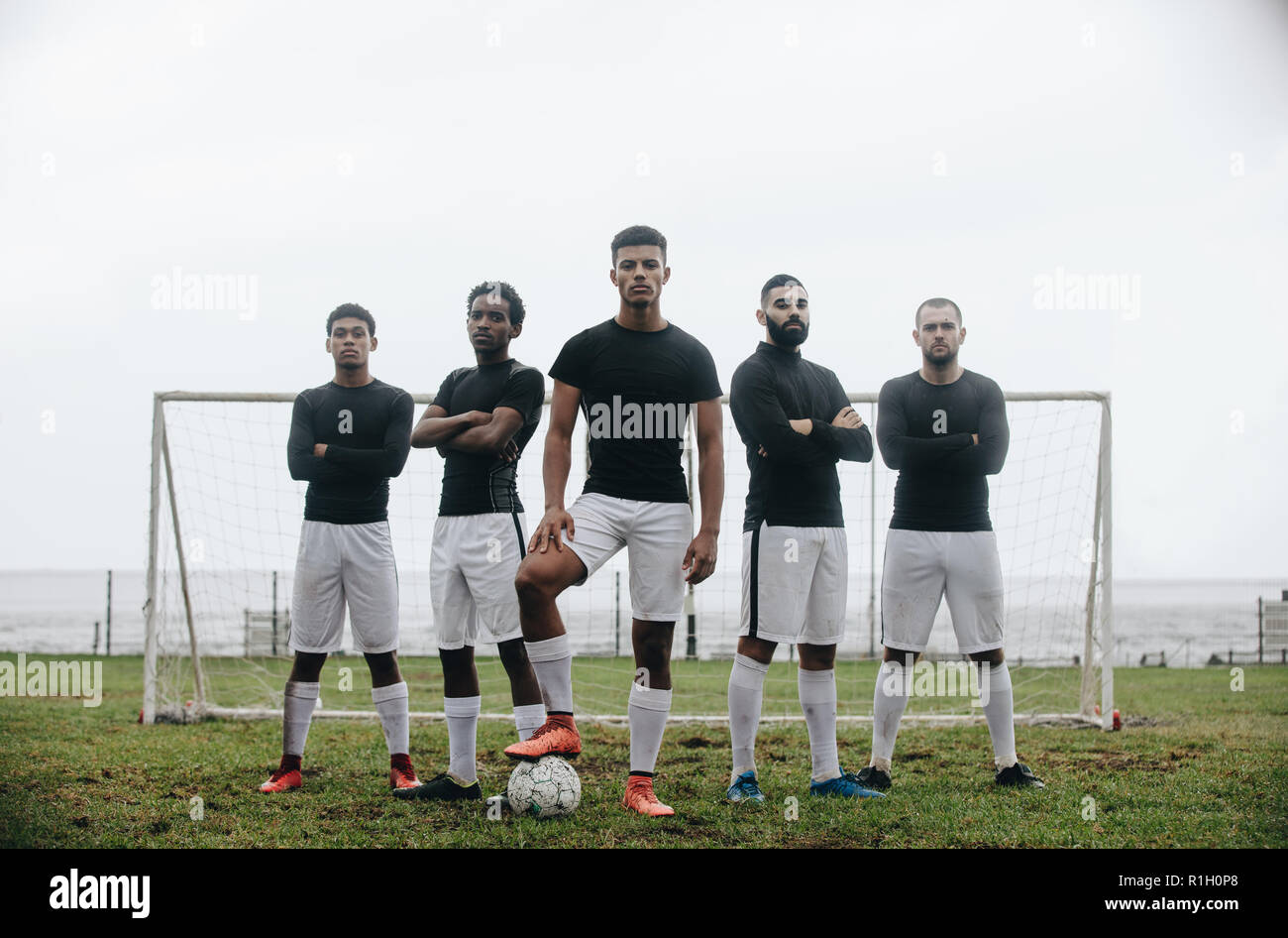 Five football players standing in a formation in front of goalpost ...