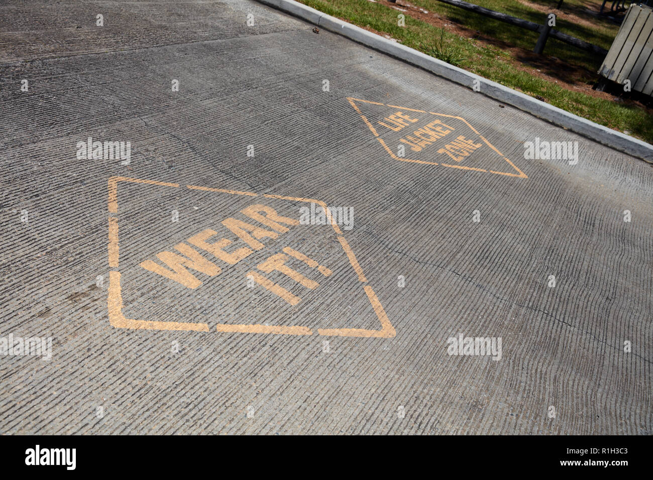 Yellow painted life jacket reminder signs on the boat launch ramp in ...