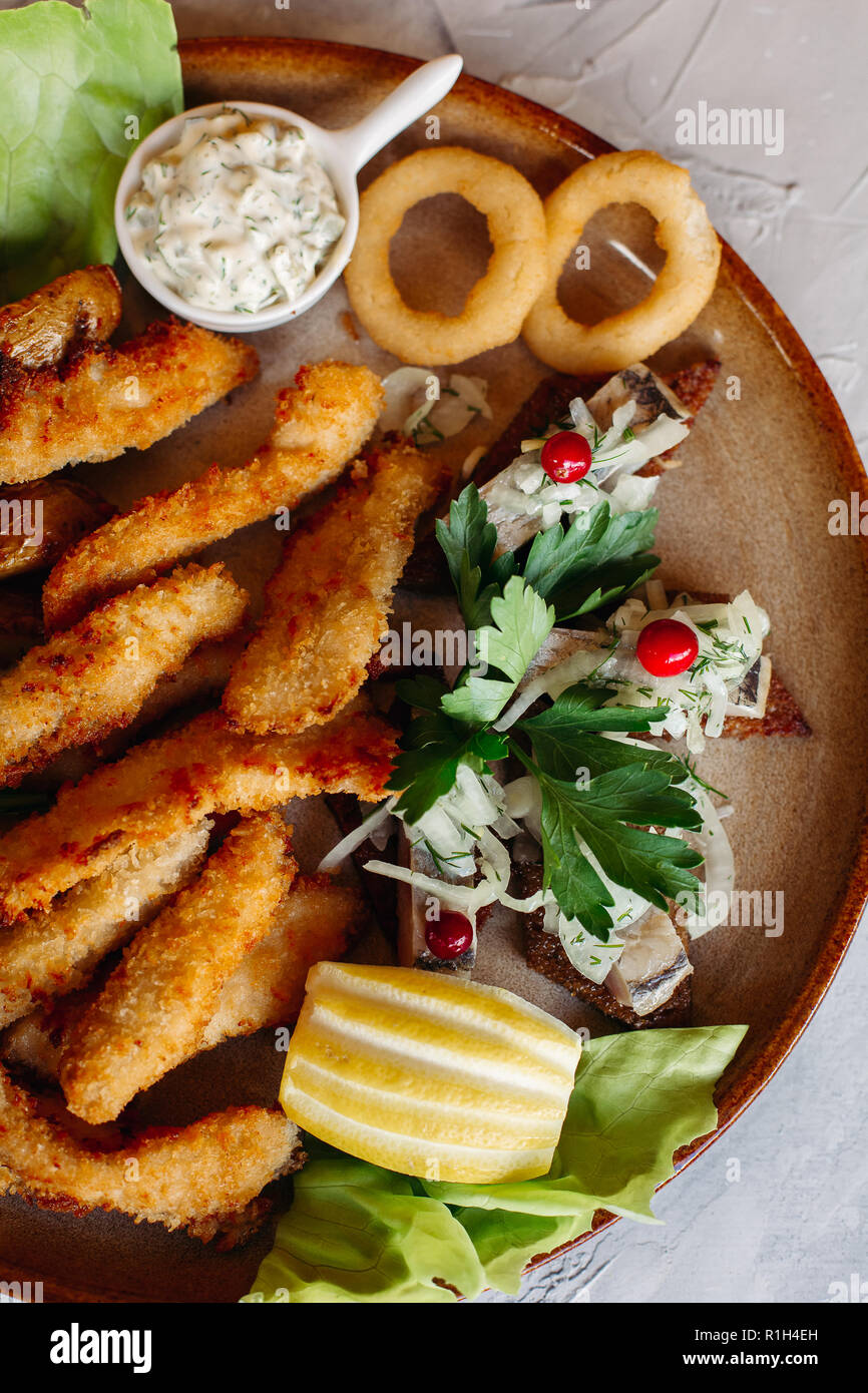 Clay plate full of delicious appetizers standing on white surface Stock ...