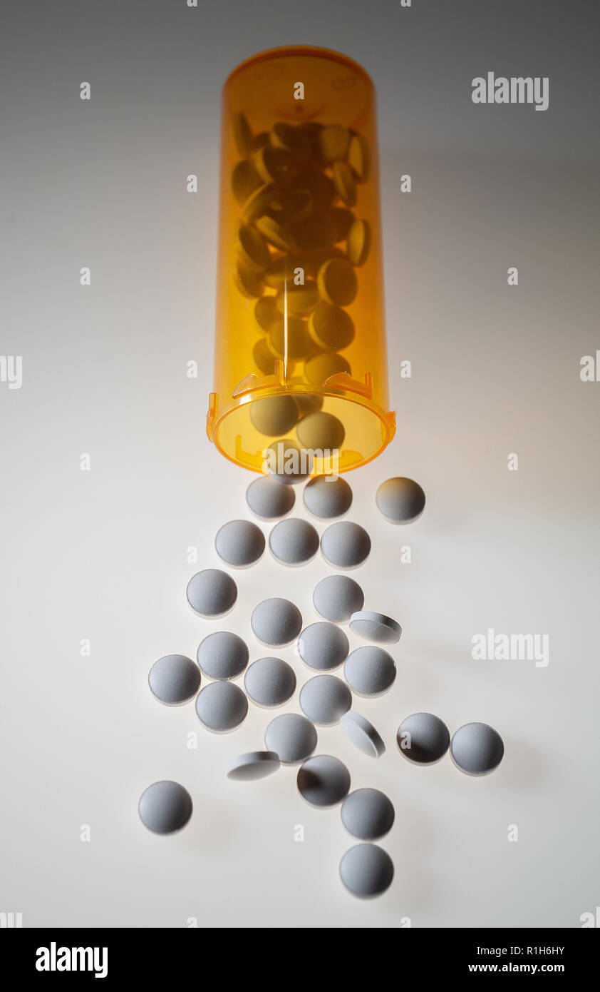 Medication pills pouring out of orange plastic bottle Stock Photo - Alamy