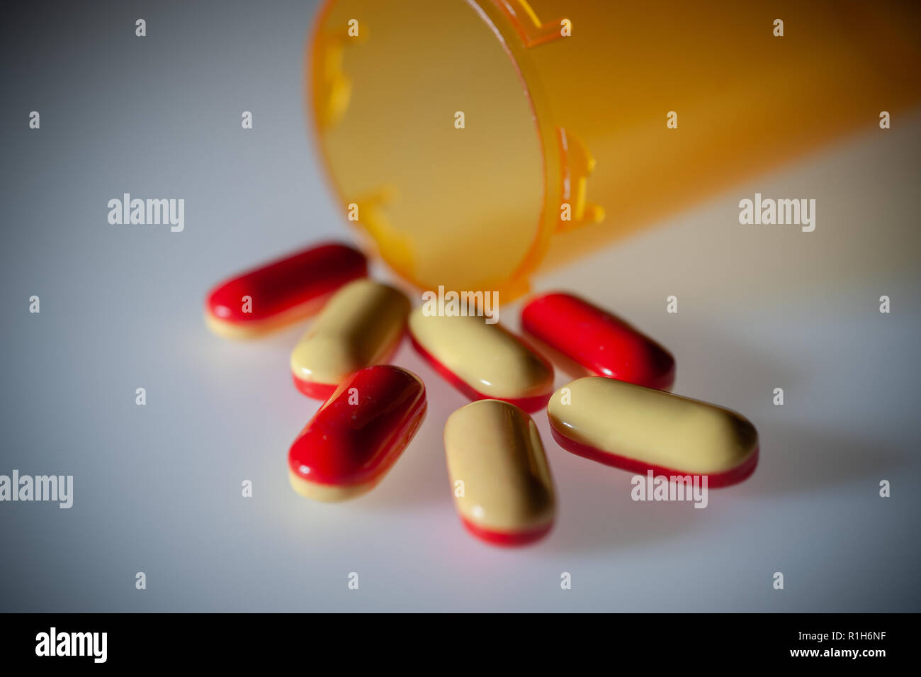 Medication pills pouring out of orange plastic bottle Stock Photo - Alamy