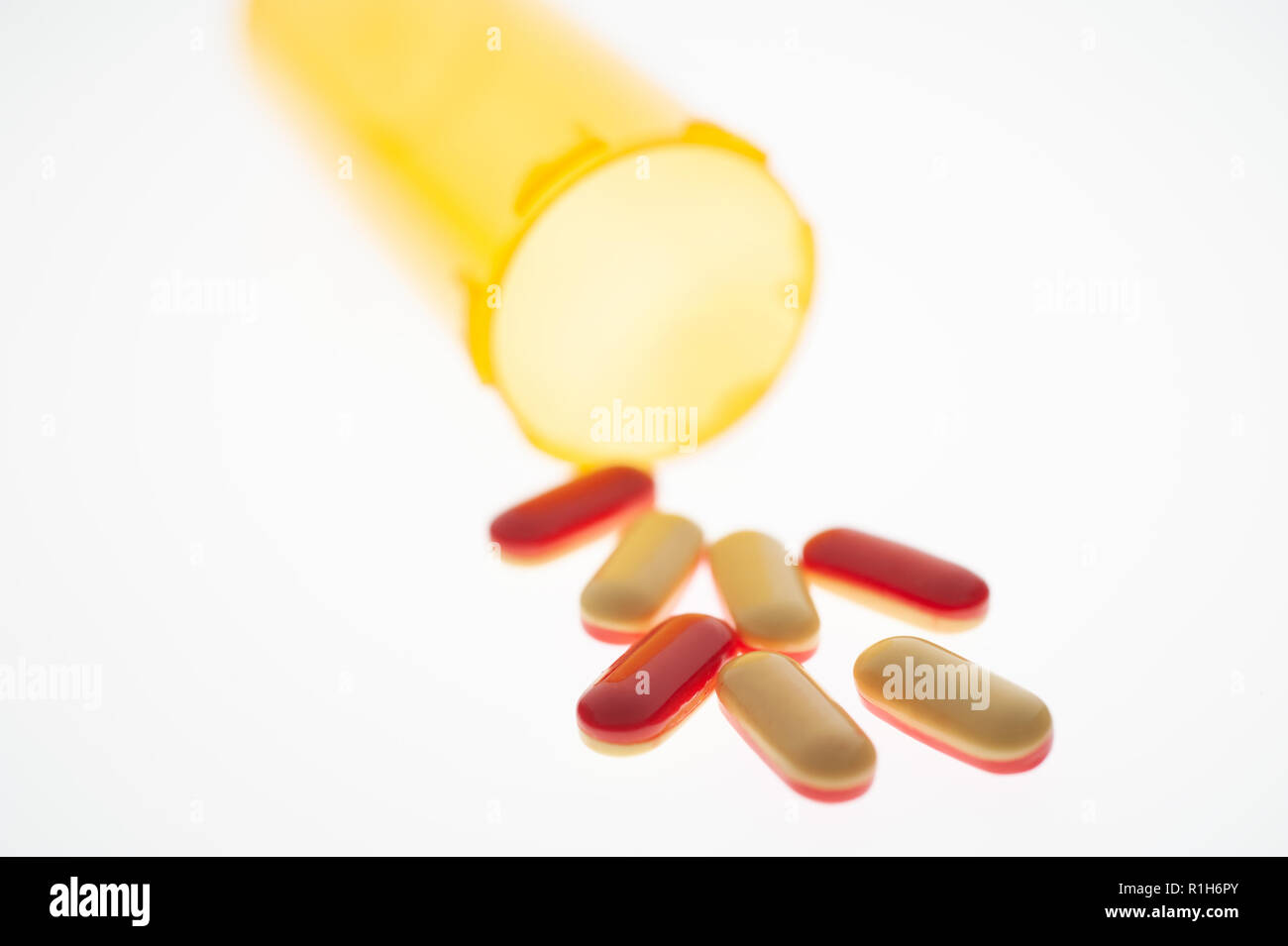 Medication pills pouring out of orange plastic bottle Stock Photo - Alamy