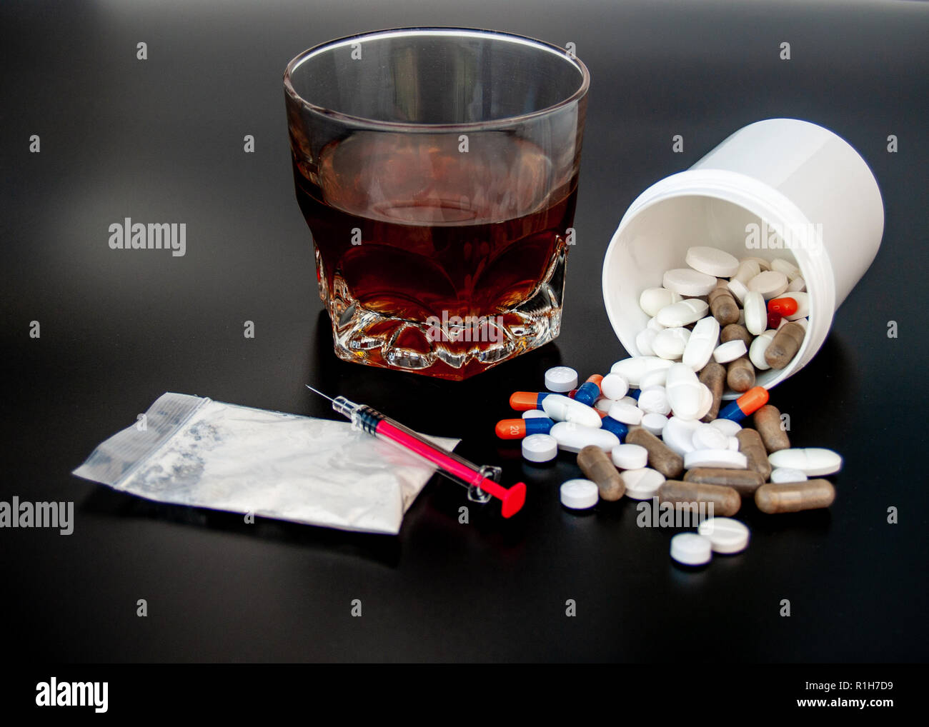 Pills of different sizes, shapes and colors, a glass of whiskey, drugs ...
