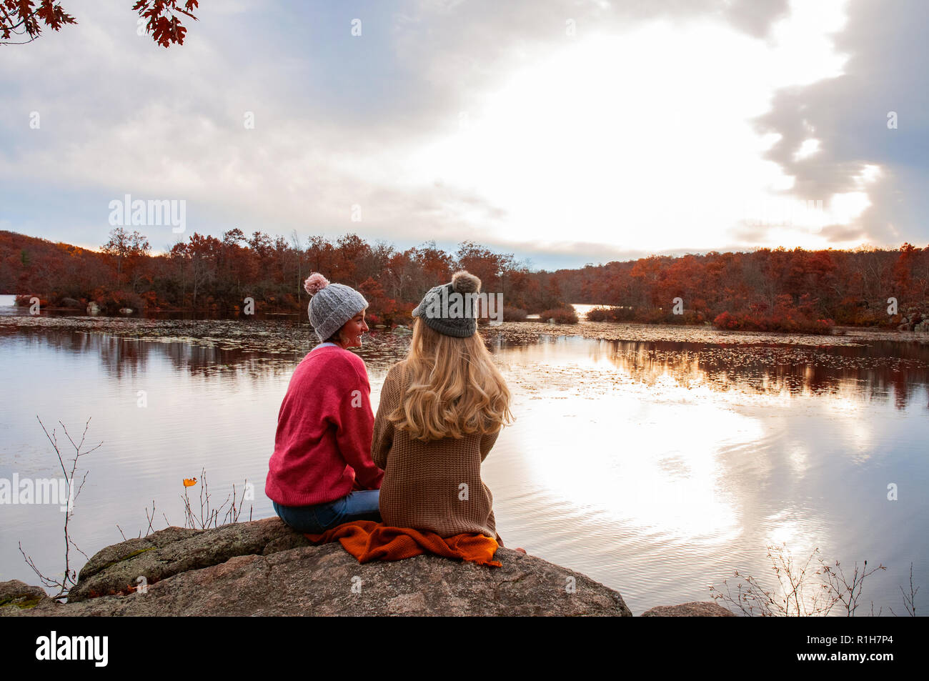 Two girls traveler in autumn clothes looking at amazing lake and forest ...