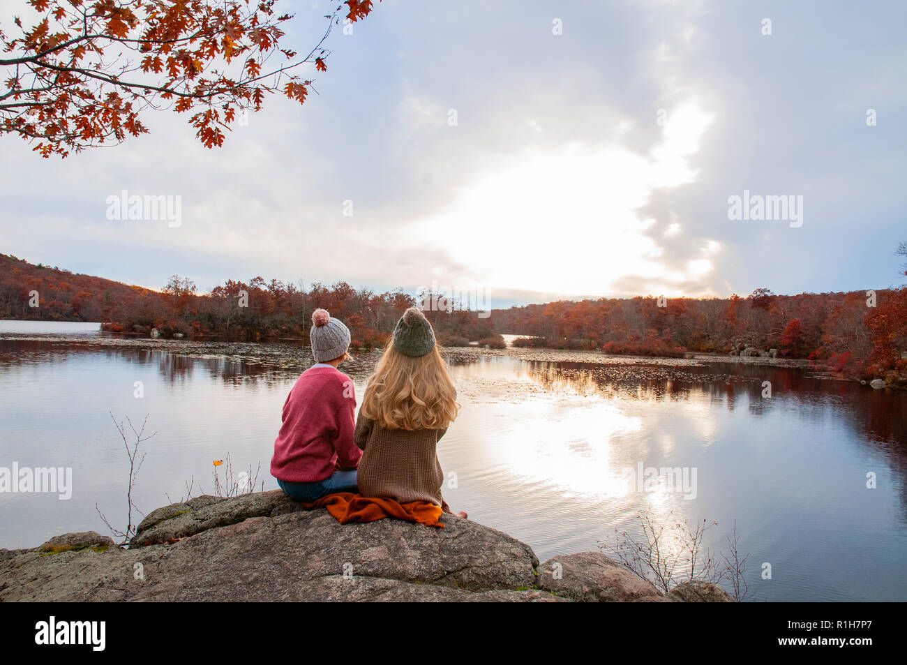 Two girls traveler in autumn clothes looking at amazing lake and forest ...