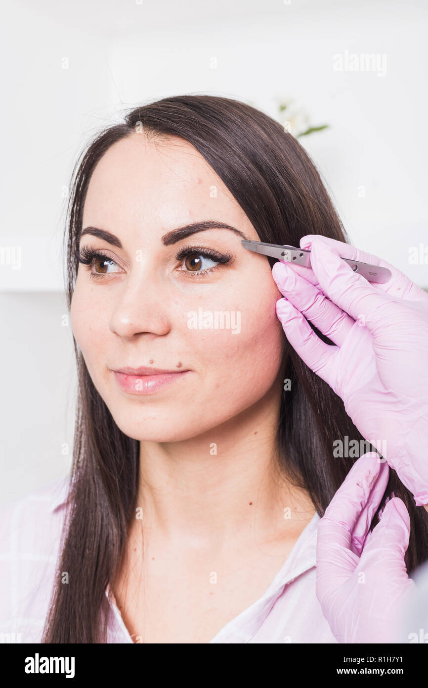 Forming eyebrows shape. Cosmetic procedures in cosmetology office. Face ...