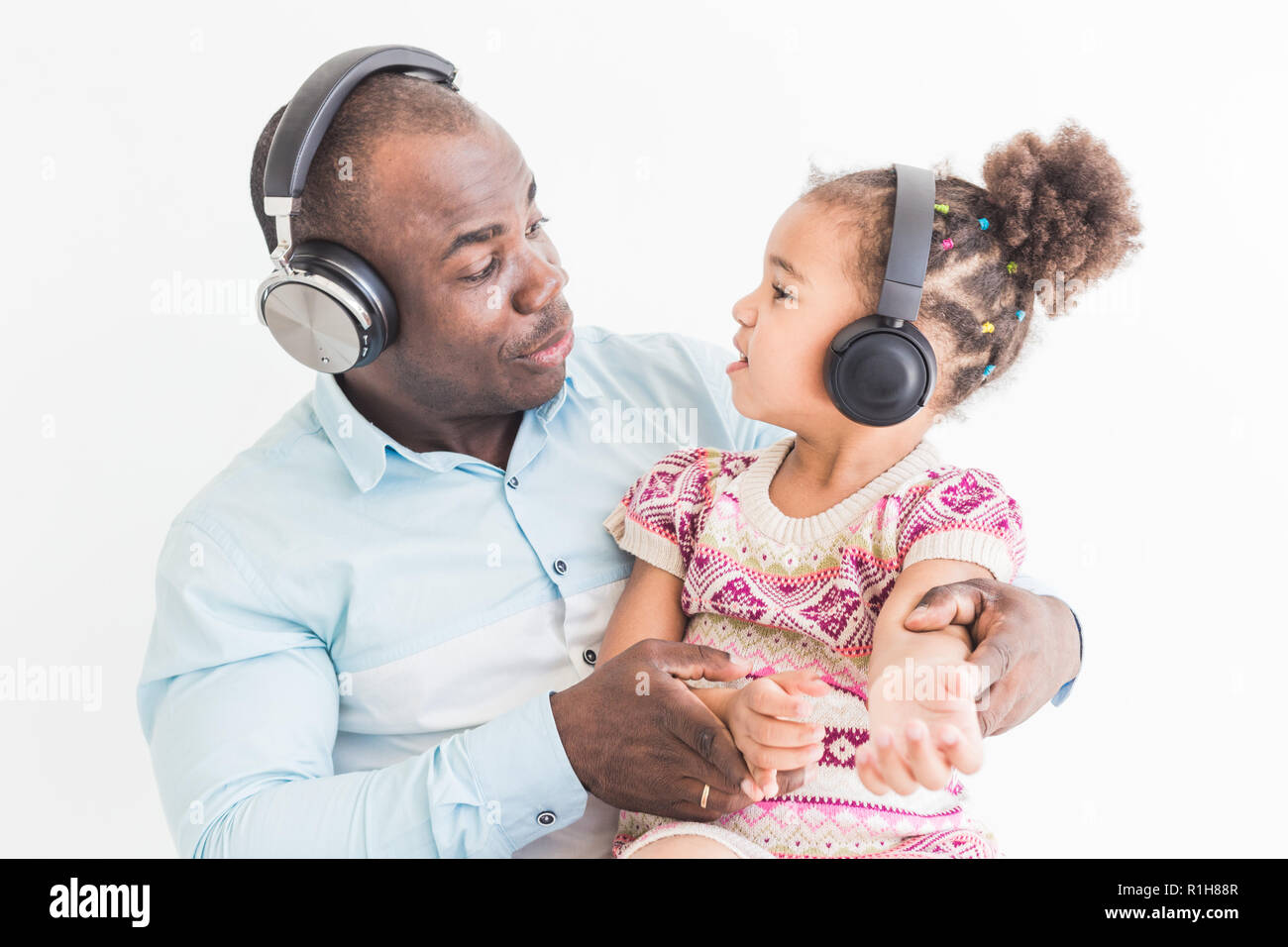 Cute little girl and her dad are listening to music with headphones on ...