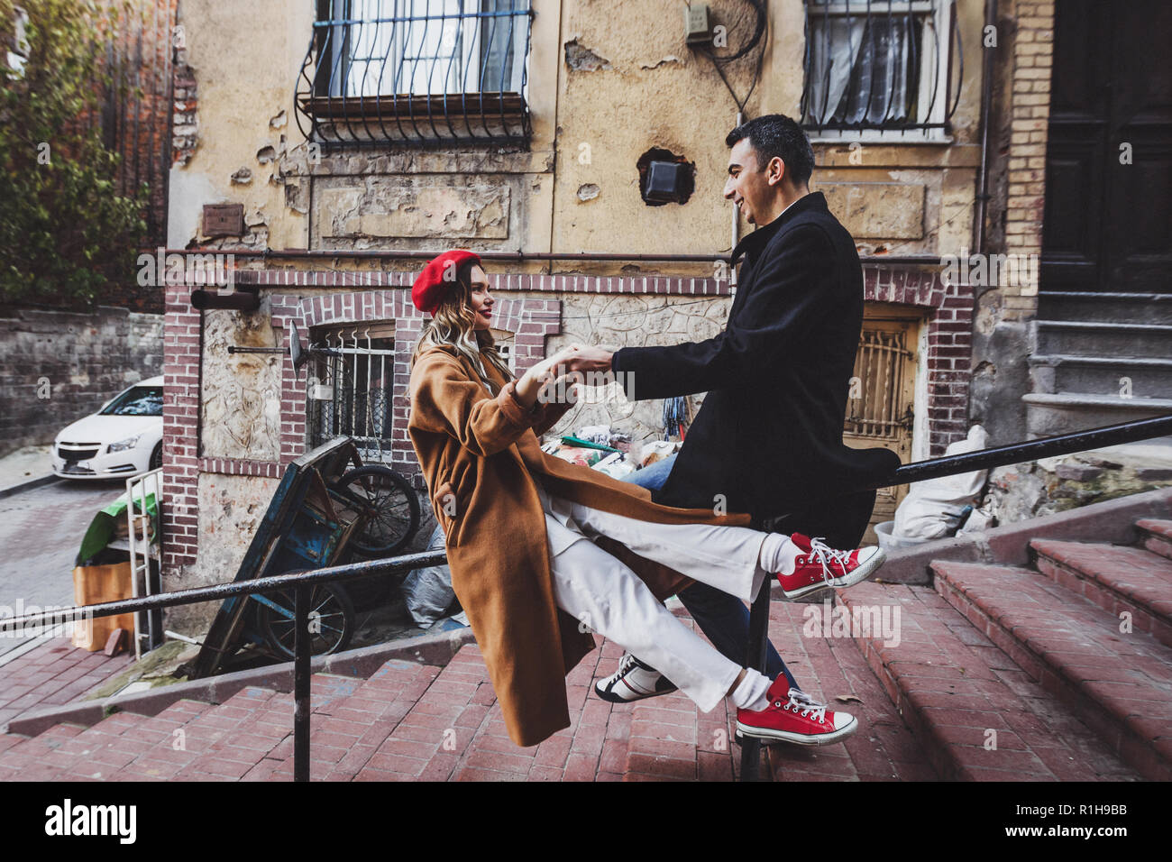 Woman funny slides down the stair railing. Young couple having fun ...